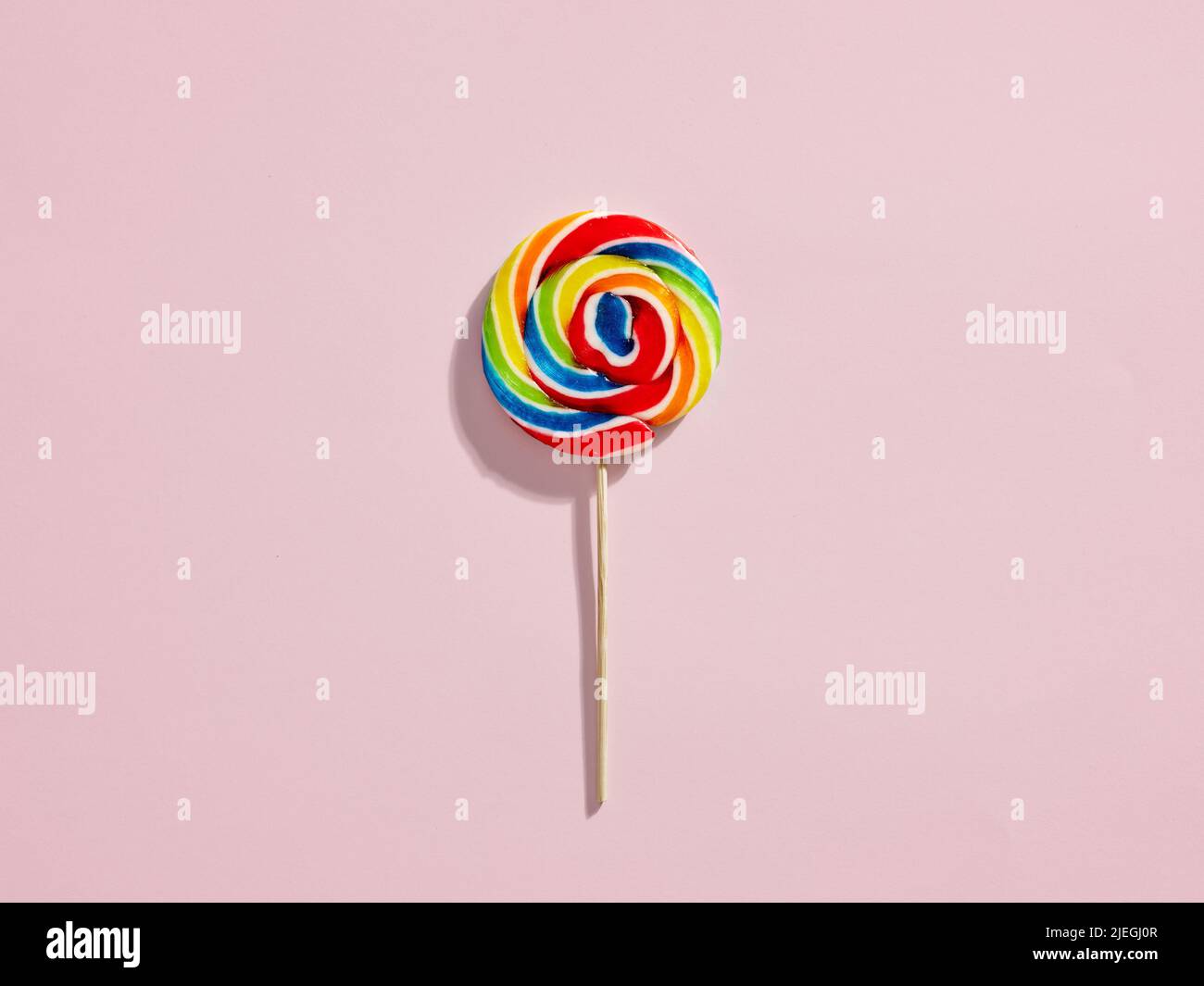 Rainbow colored swirl round candy lollipop on pink background Stock ...