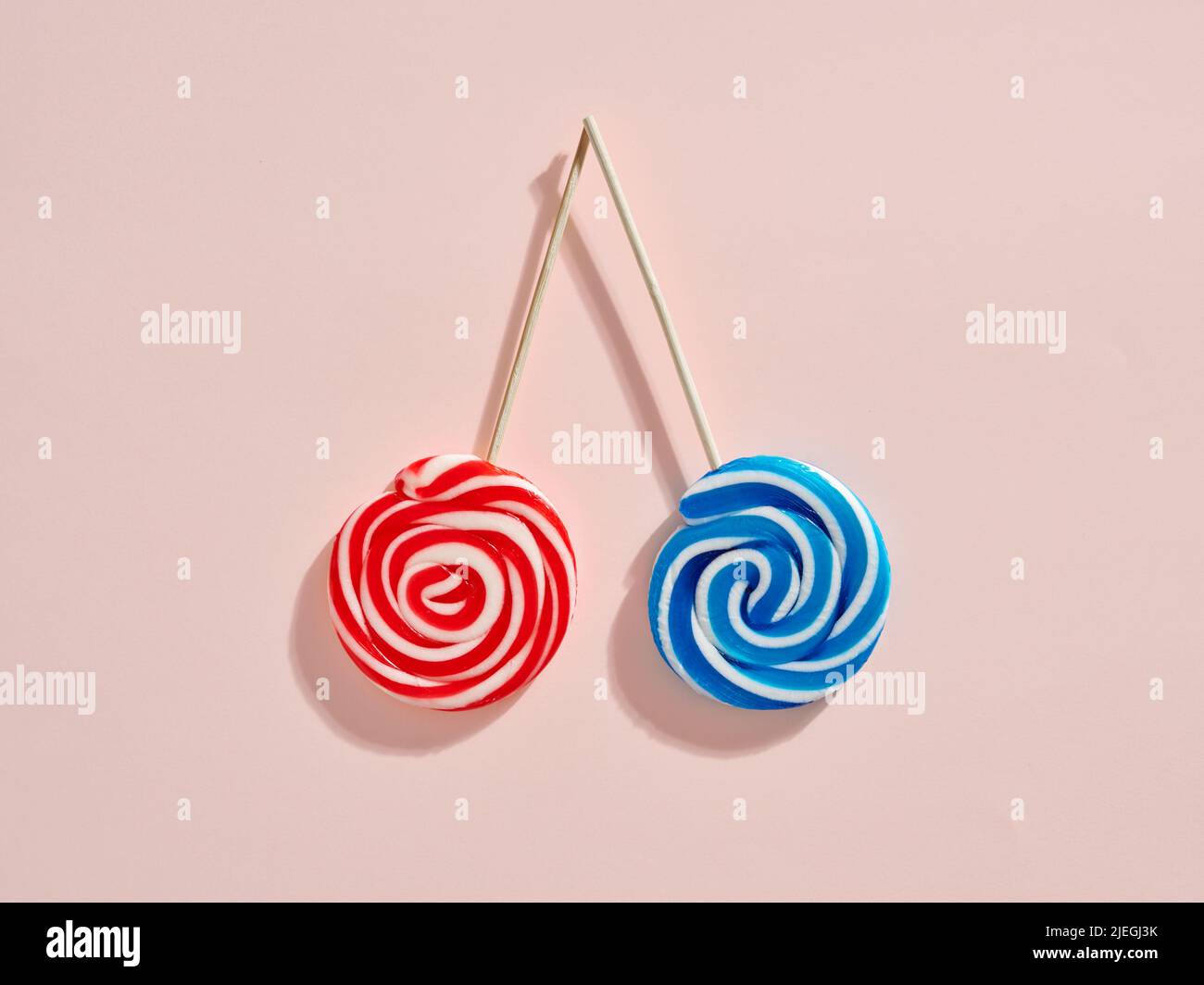 Colorful swirl round candy lollipops designed as cherry shape on pink ...