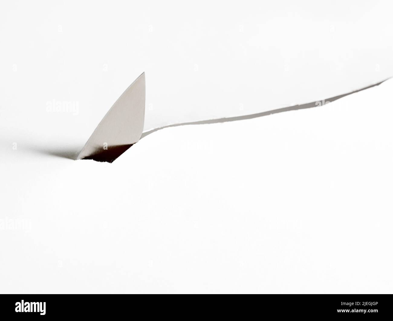Knife blade cutting through surface from underneath resembling a shark ...