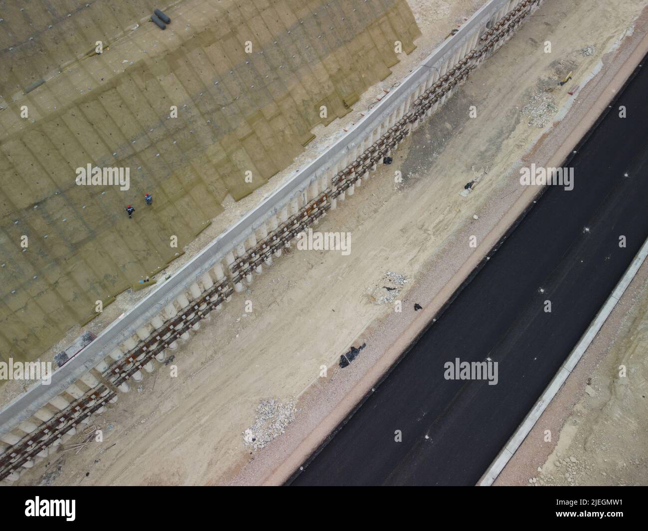 Workers reinforce the slope over the new road. Road construction in ...
