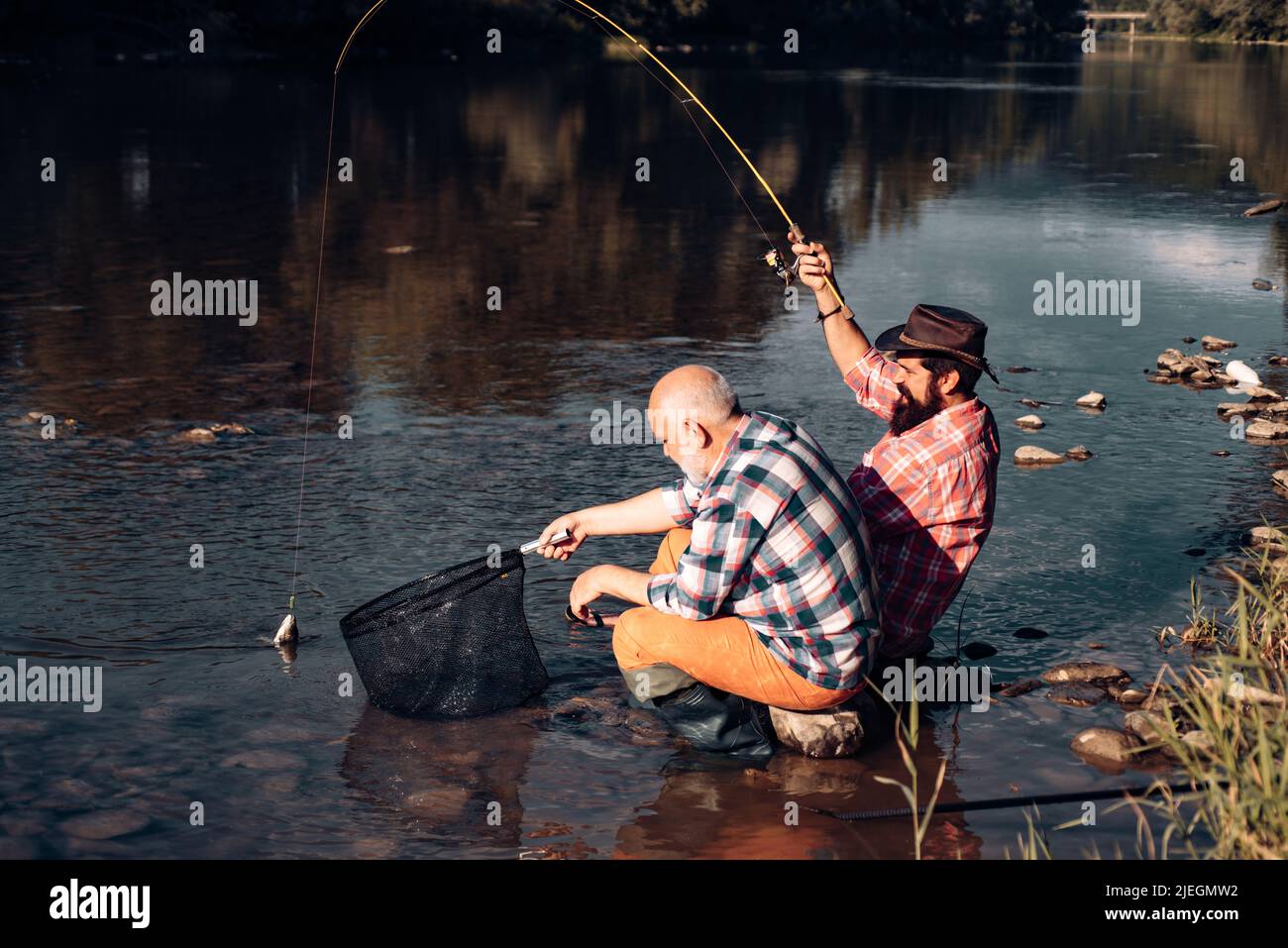 Portrait of cheerful senior man fishing. Grandfather and son fishermans ...