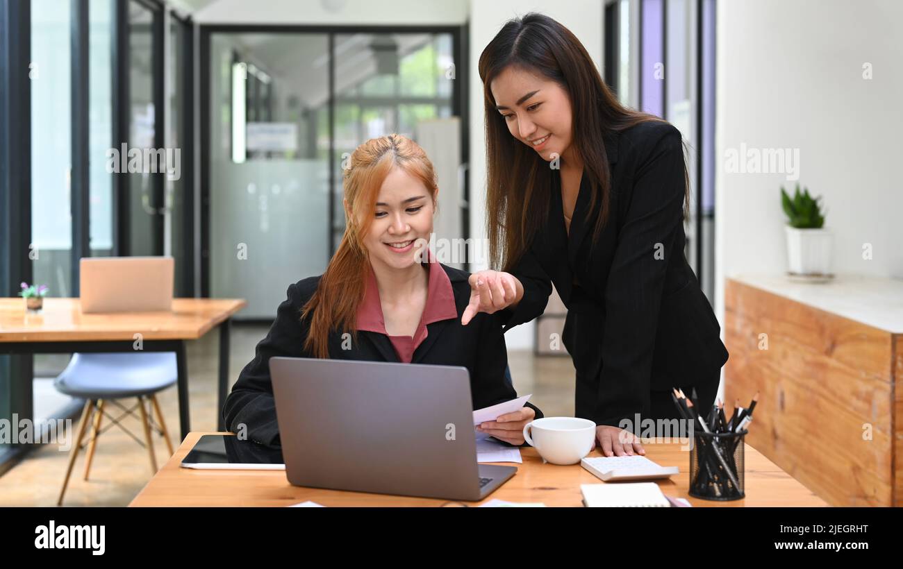 Asian female manager helping, giving advices to young intern at ...