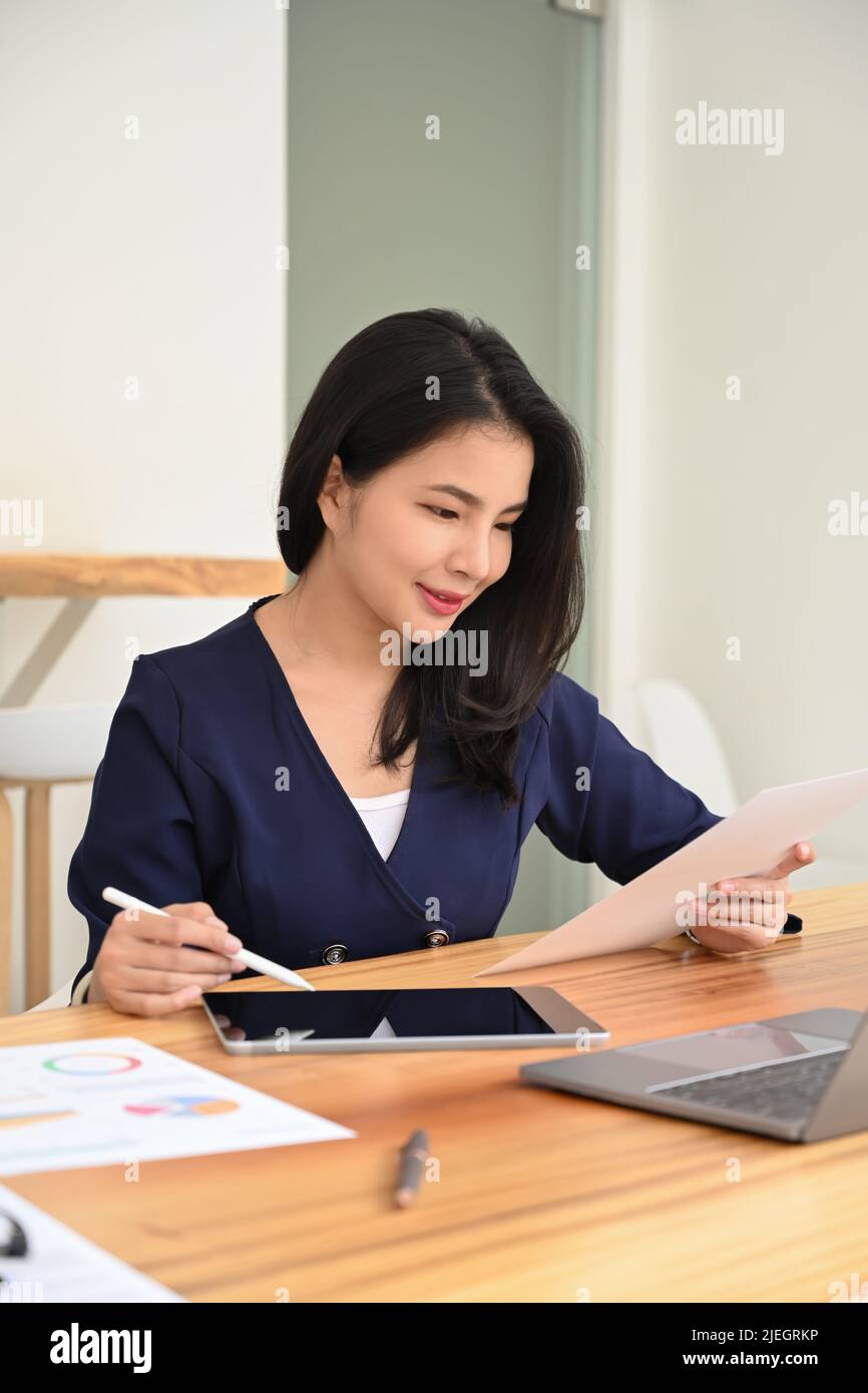 Attractive young business woman holding financial reports and using ...