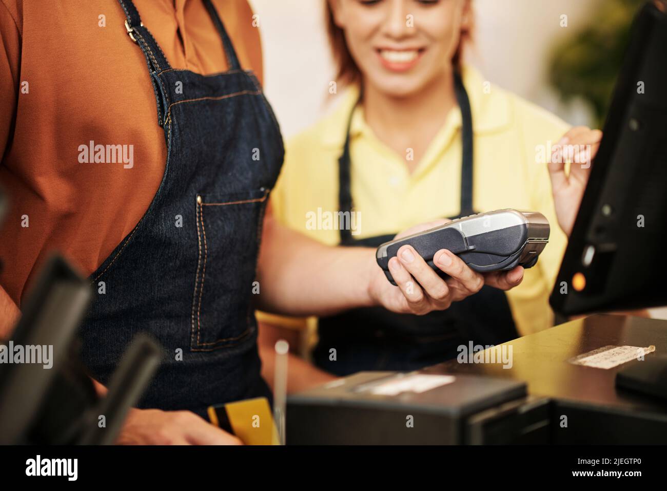 Cafe owner showing new worker how to print receipts after accepting ...