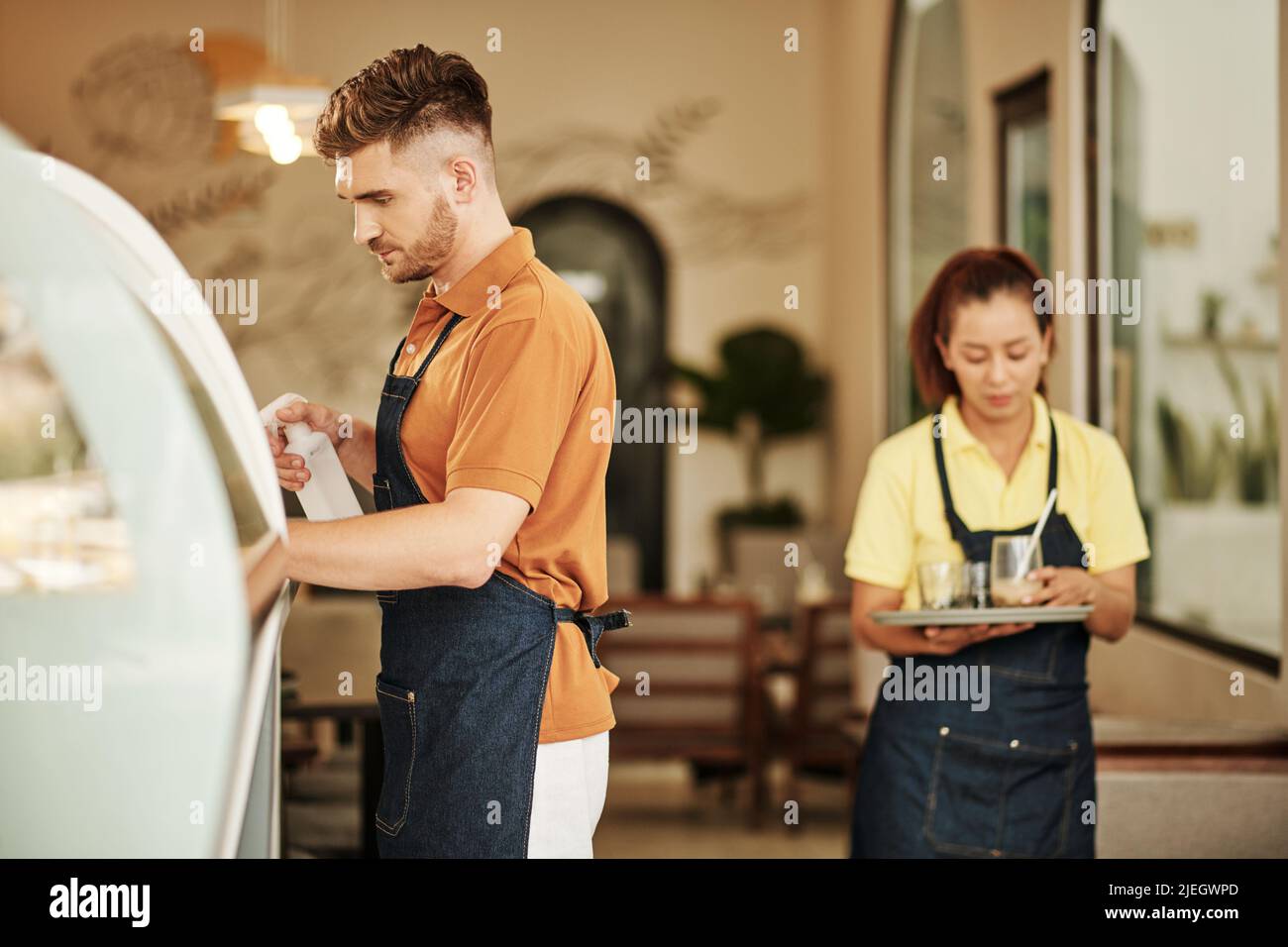 Waiter carrying tray with dirty glasses in kitchen when barista ...