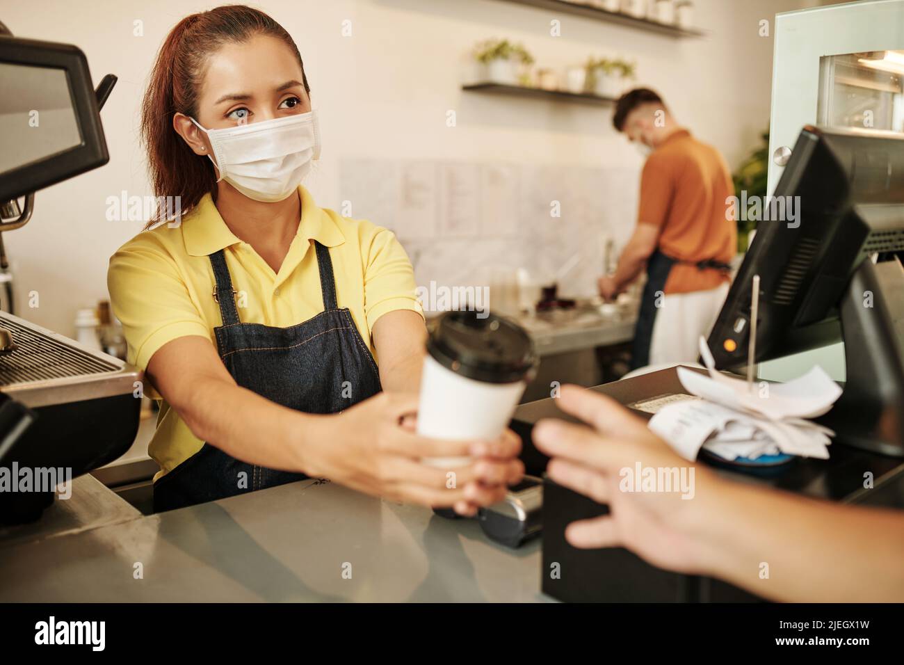 Coffeeshop barista wearing medical mask when selling cup of take out ...