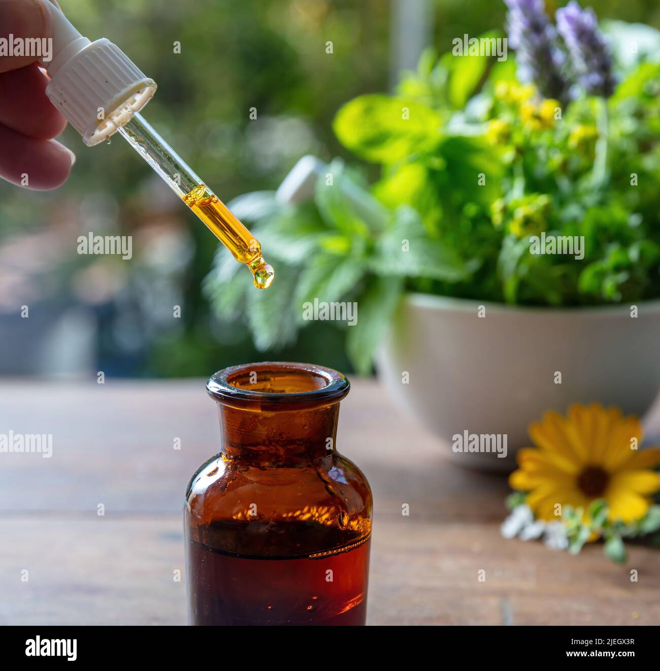 Essential oil drop falling in a glass bottle, close up. Alternative ...