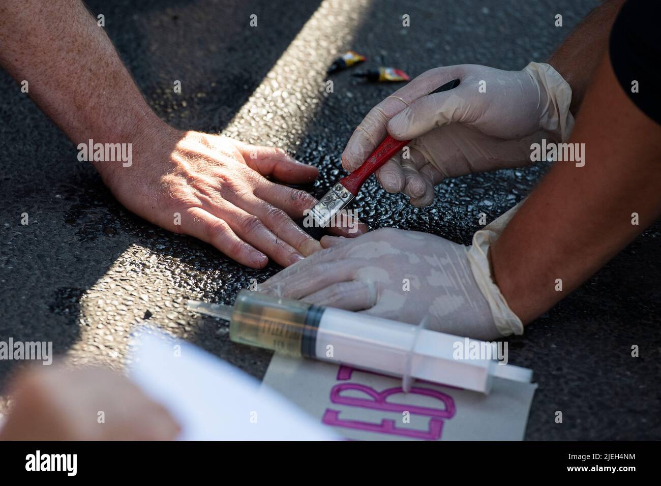 Berlin, Germany. 27th June, 2022. A police officer detaches the sticker ...