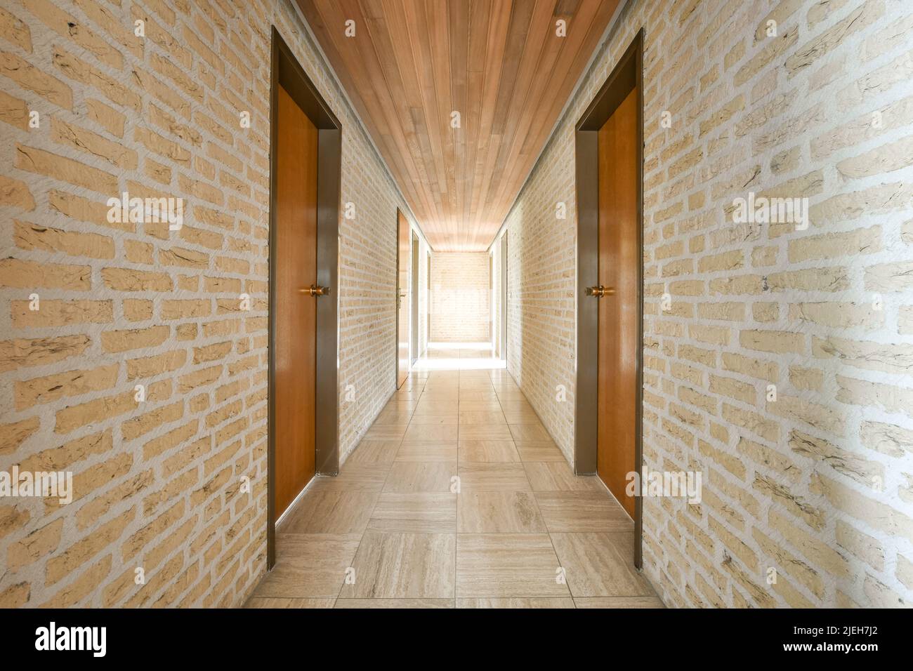 Light narrow hallway with many doors in brick walls and parquet floor ...