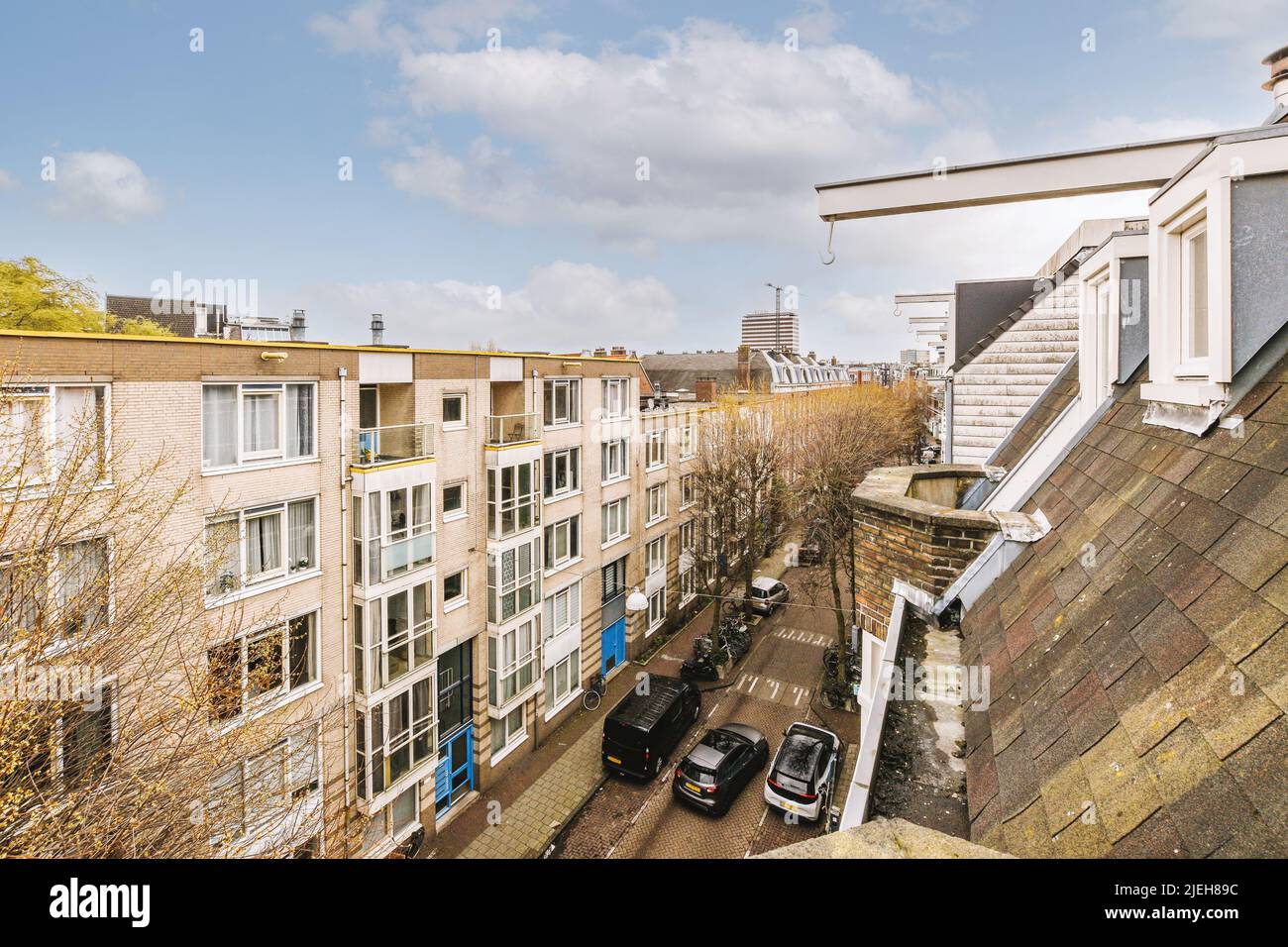 Panoramic view of old brick buildings with parking and trees from small ...