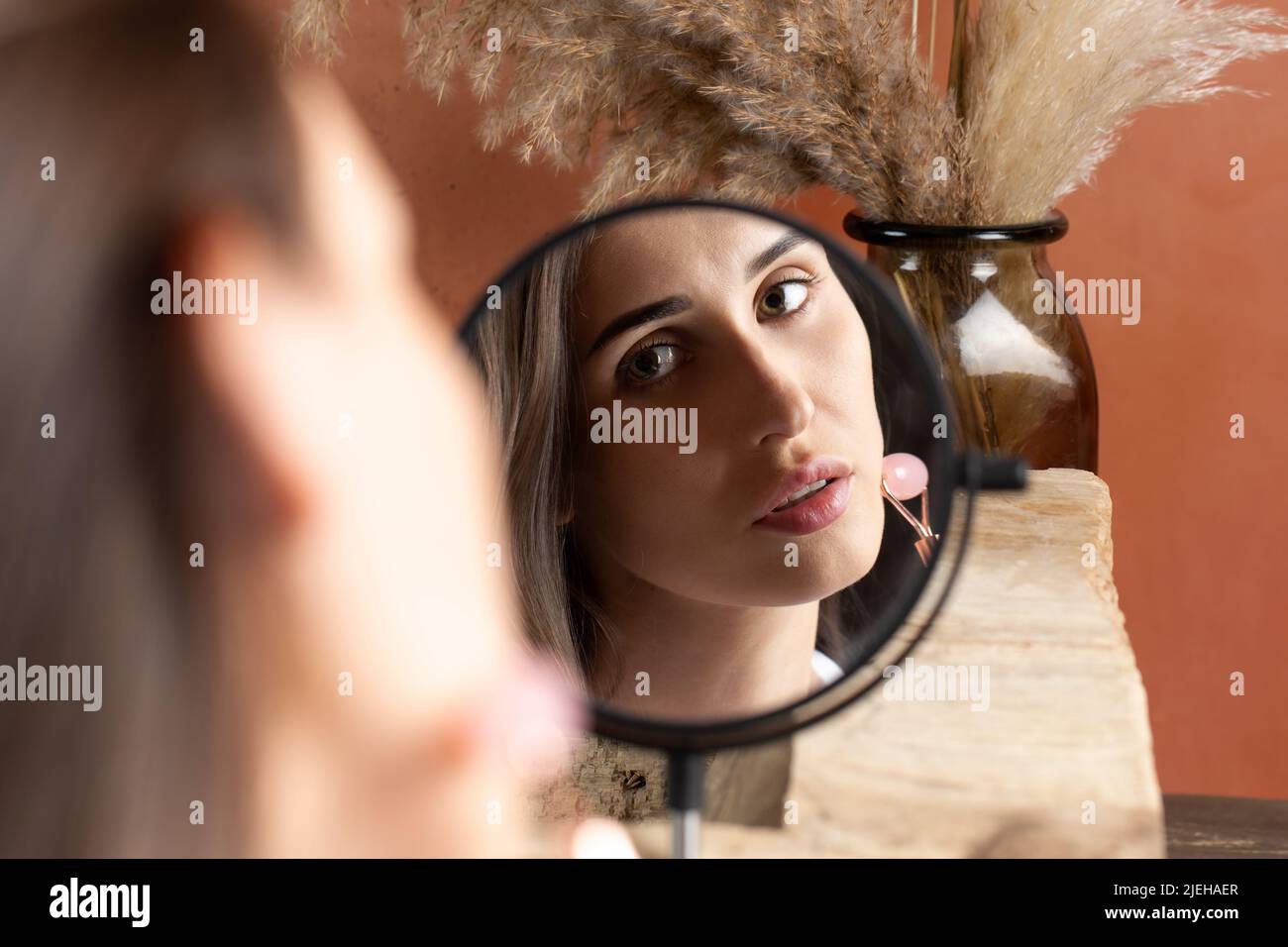 A beautiful brunette girl in the reflection of a mirror does a facial ...