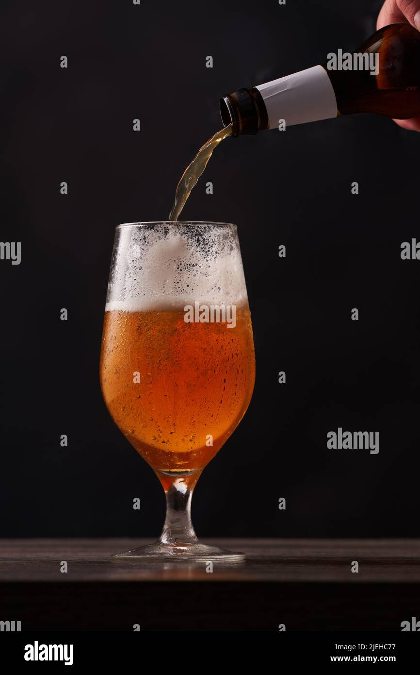 Pouring beer into glass at the bar counter. Alcoholic beverage over pub ...
