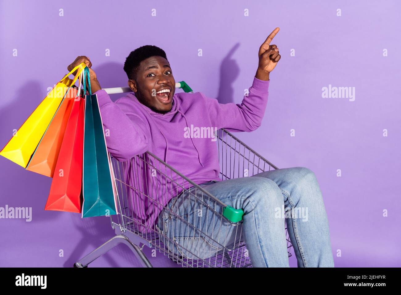 Portrait of astonished funny man indicate finger empty space sit ...