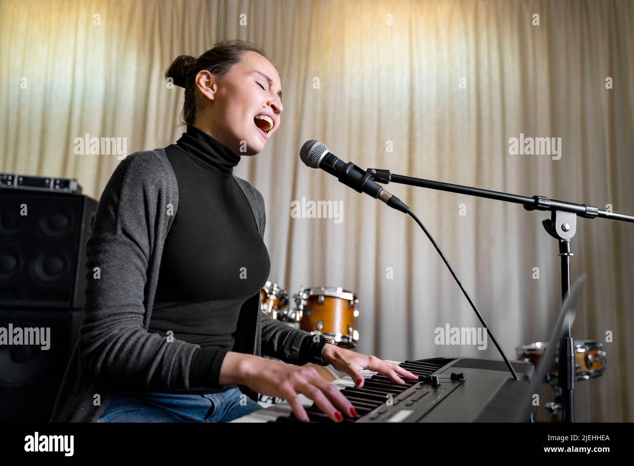 Young Asian or Caucasian woman singing song loud on mic, playing ...