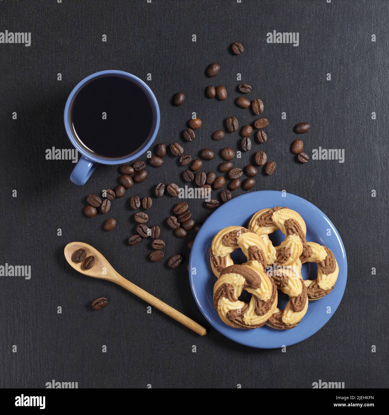 Sweet cookies and coffee in blue dishes on black stone background, top ...