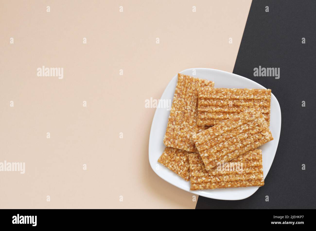 Sesame Bars with Peanuts in plate on two-tone background, top view with ...