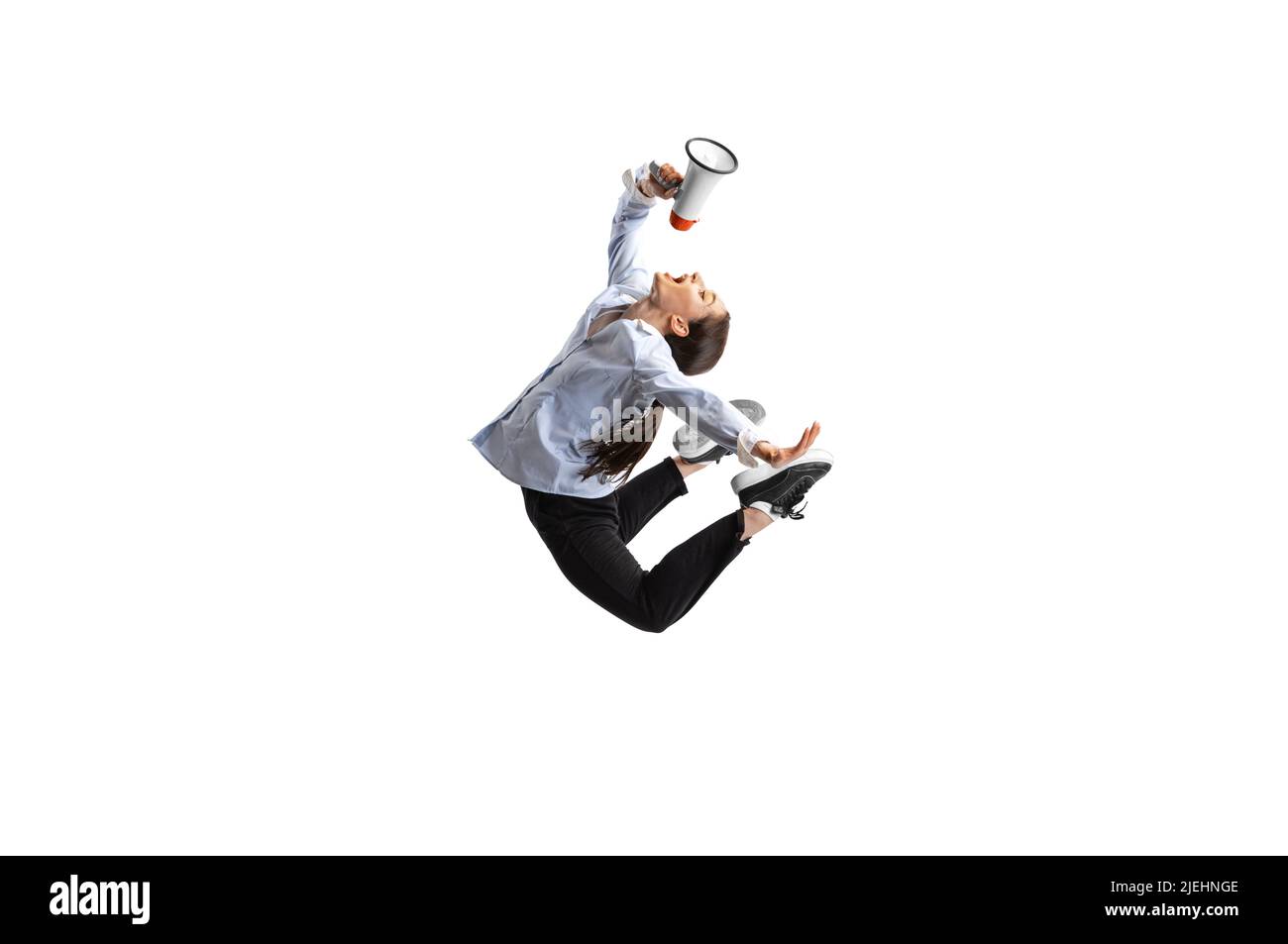 Portrait of young woman, office worker shouting in megaphone in a jump ...