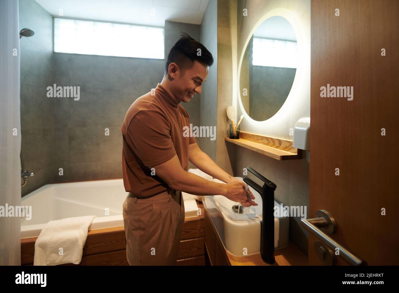 Positive young man washing hands after coming home from work Stock ...