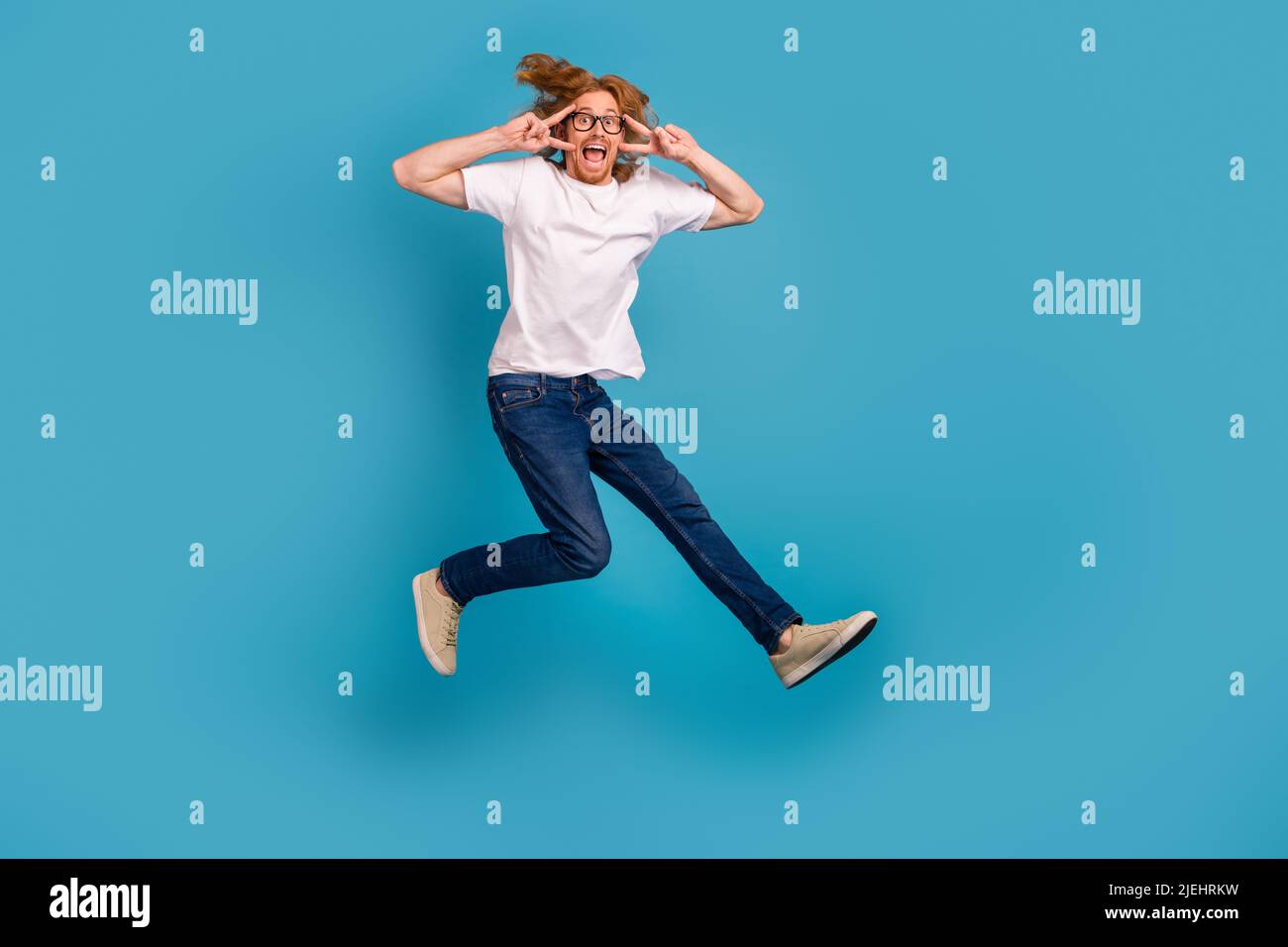 Full body photo of carefree crazy man jumping demonstrate v-sign near ...