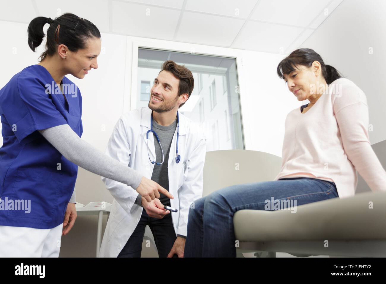 young male doctor checking knee reflexes of female patient Stock Photo ...