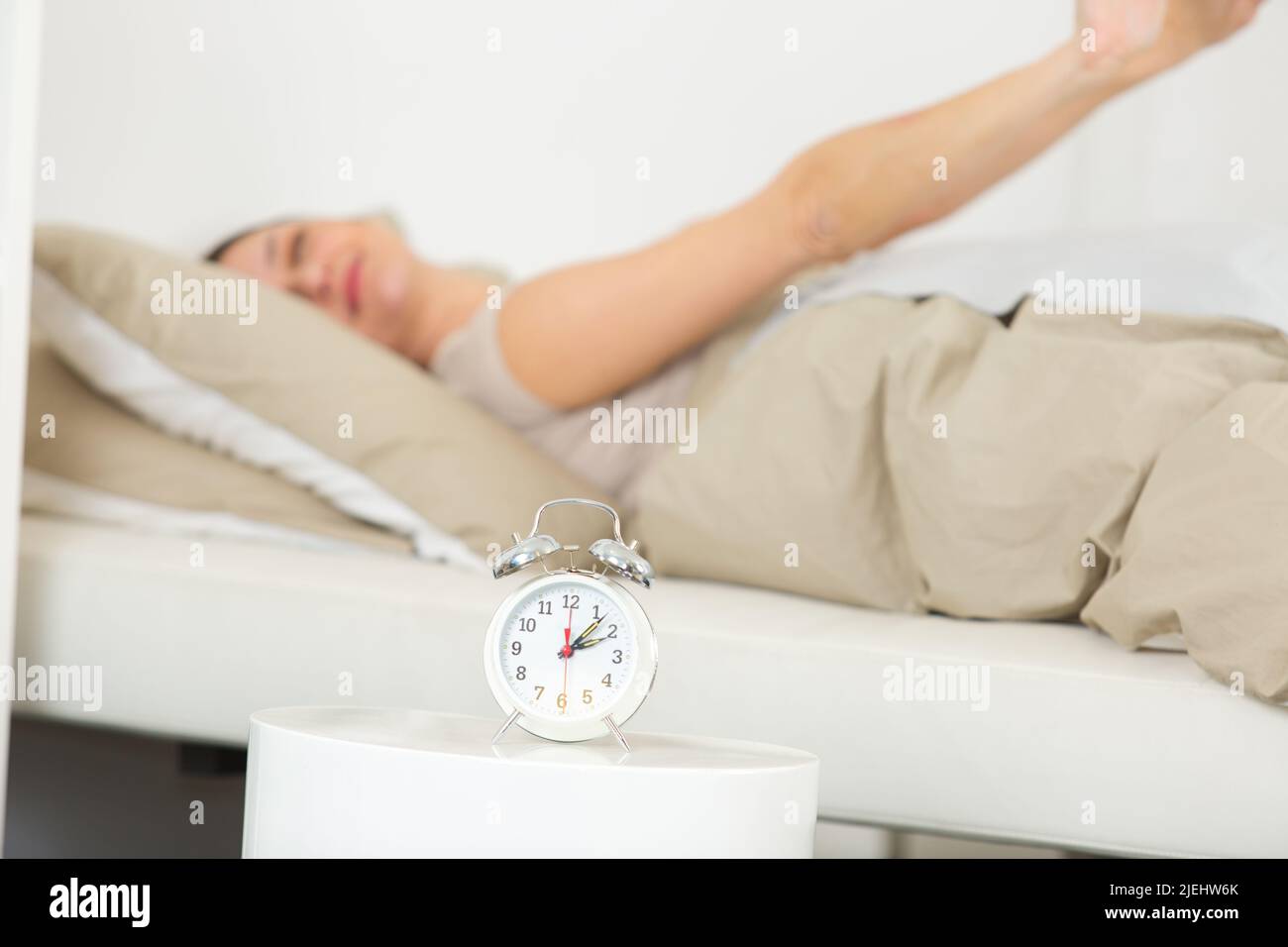 woman stretching in bed as alarm clock sounds Stock Photo - Alamy