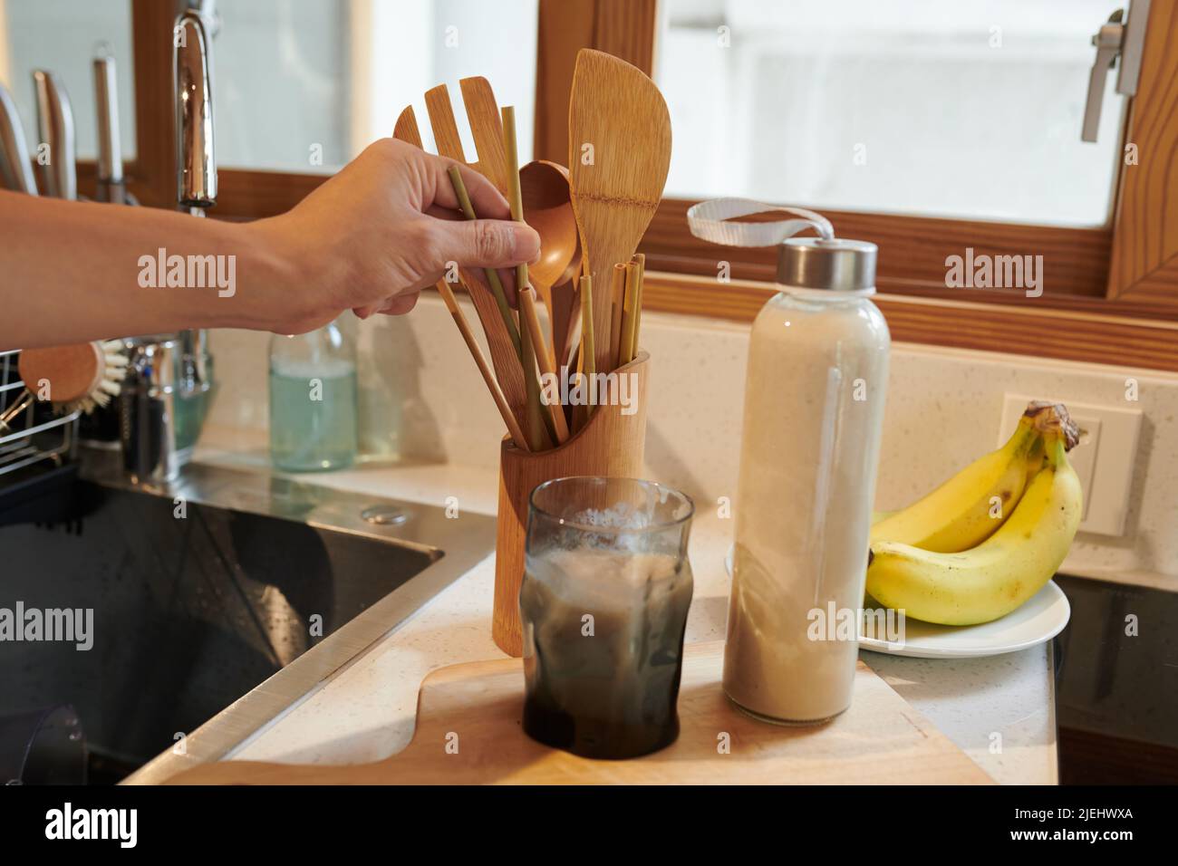Hand of man taking reusable bamboo straw to drink protein banana shake ...