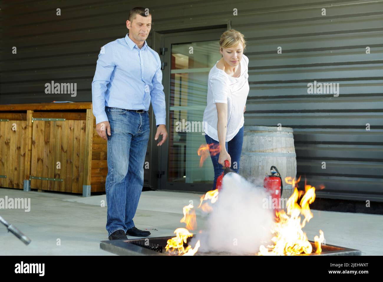 a woman demonstrating how to use a fire extinguisher Stock Photo - Alamy