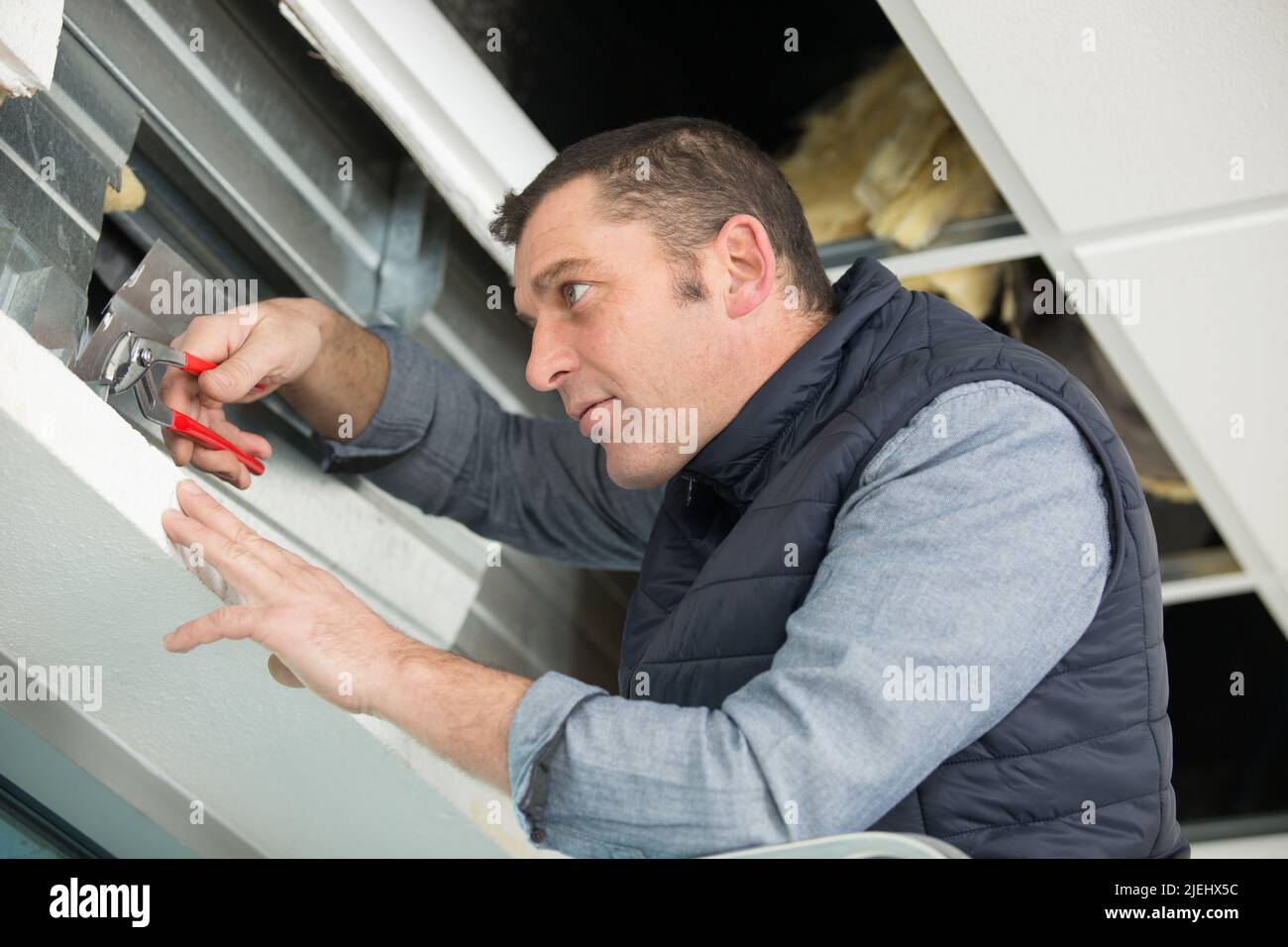 man installing roller shutter above doors Stock Photo - Alamy
