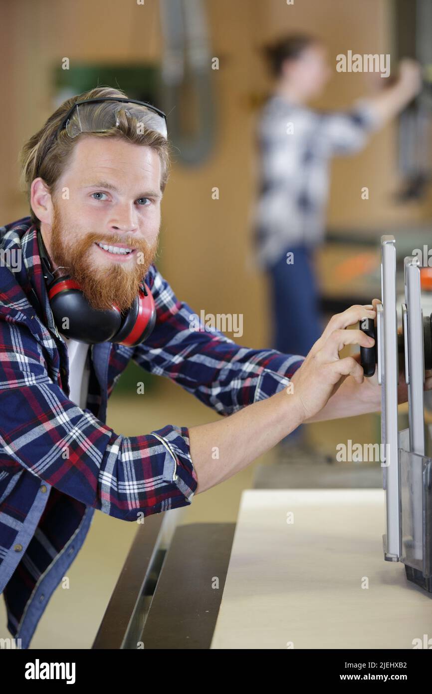 handsome carpenter is smiling while working with wood Stock Photo - Alamy