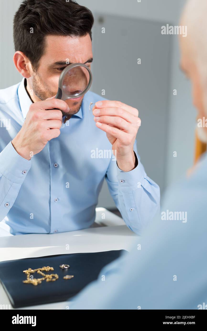 man in smart shirt looking at ring through magnifying glass Stock Photo ...