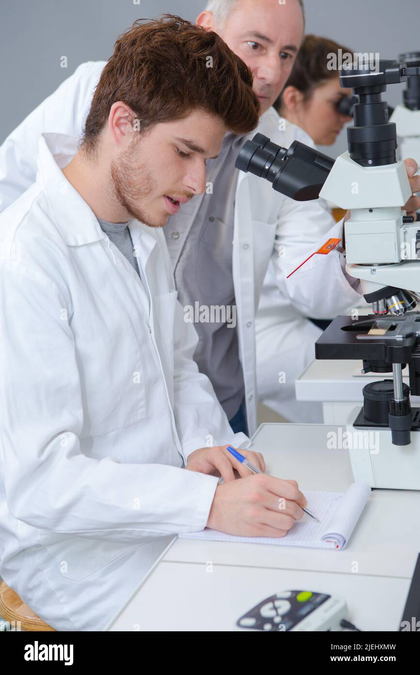 scientists with clipboard and microscope in lab Stock Photo - Alamy