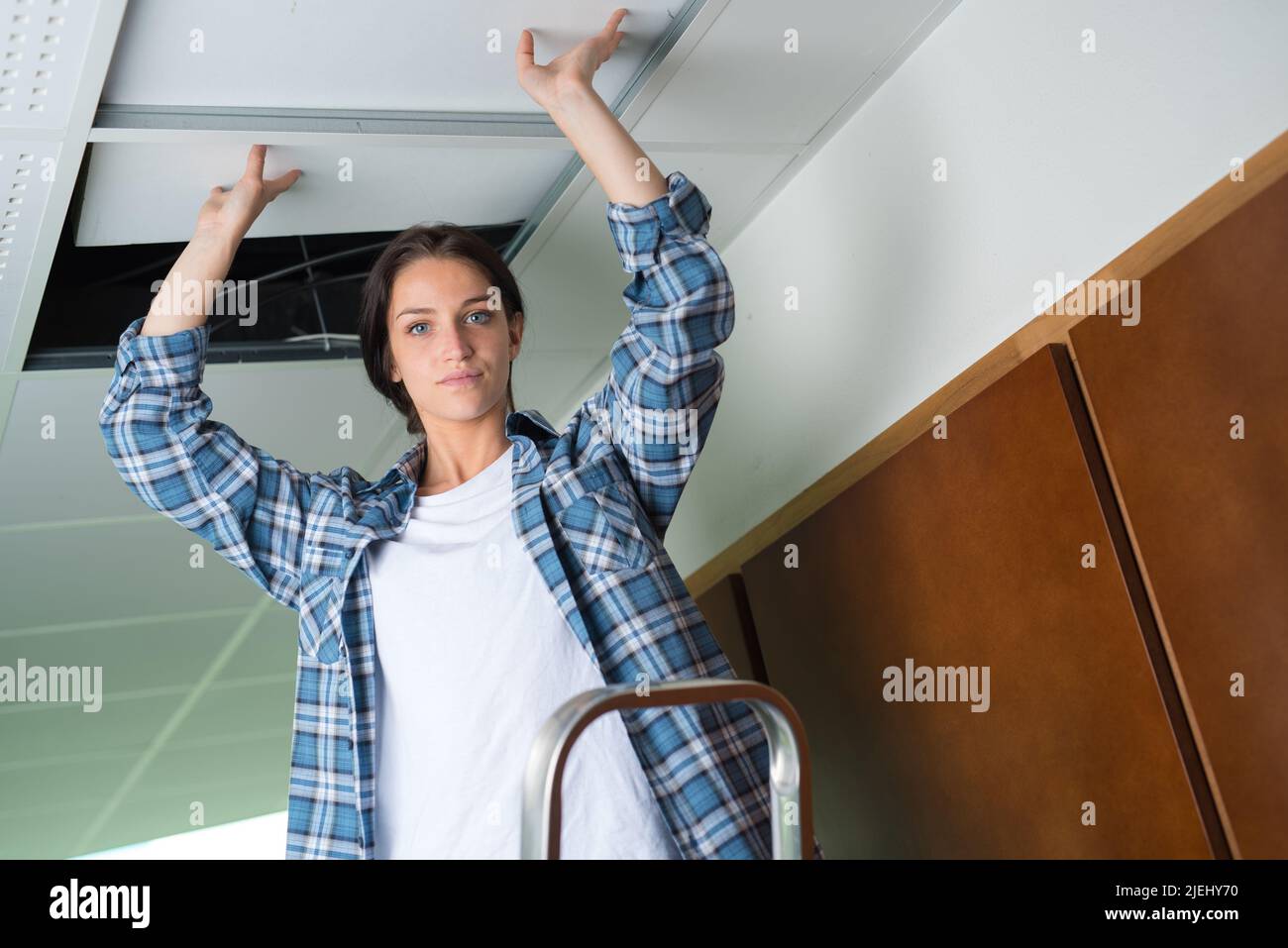 Portrait of female contractor lifting ceiling panel Stock Photo - Alamy