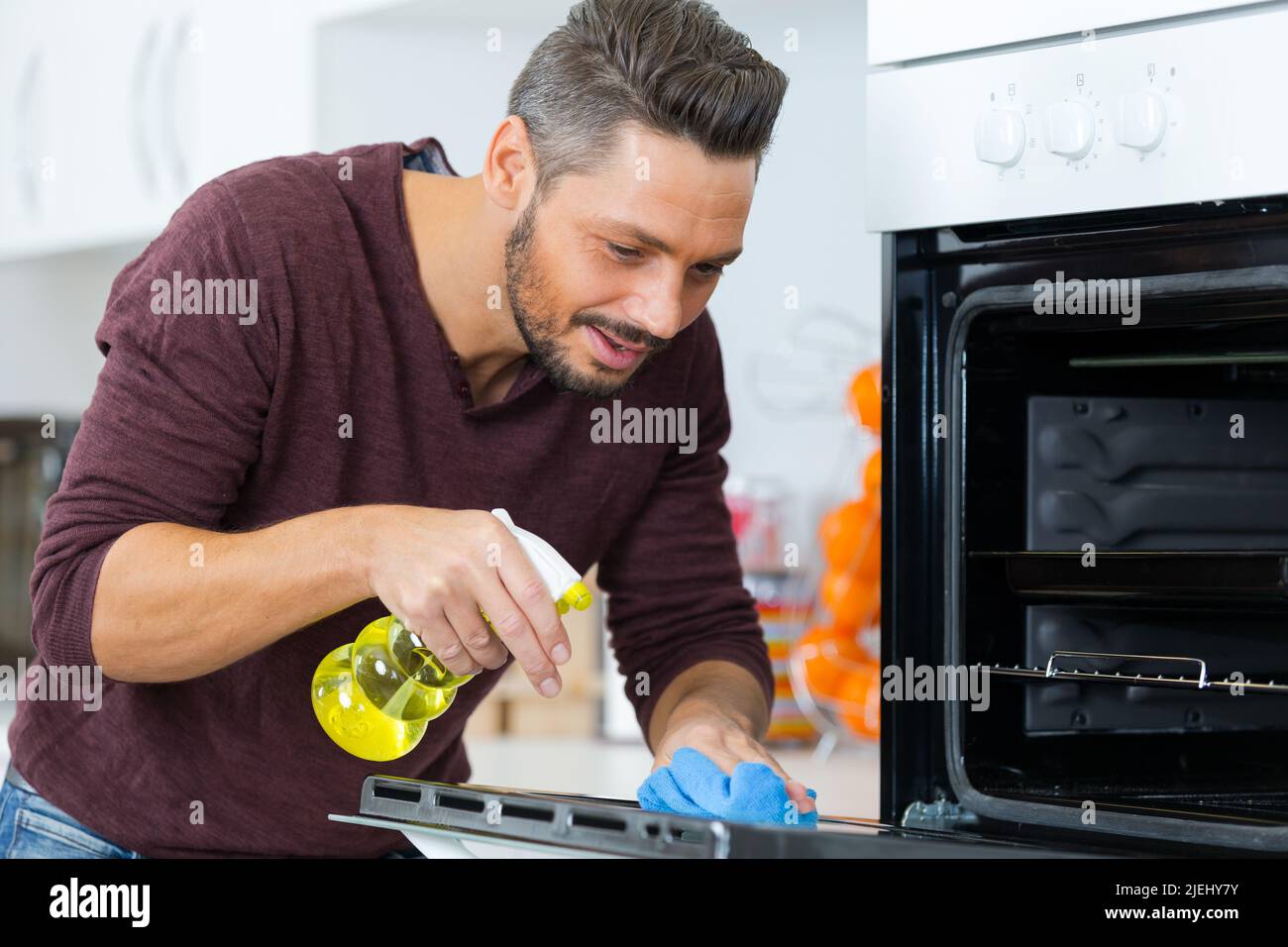 happy young man in overall cleaning oven Stock Photo - Alamy