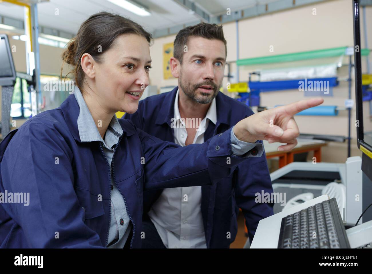 worker pointing to computer screen to show colleague Stock Photo - Alamy