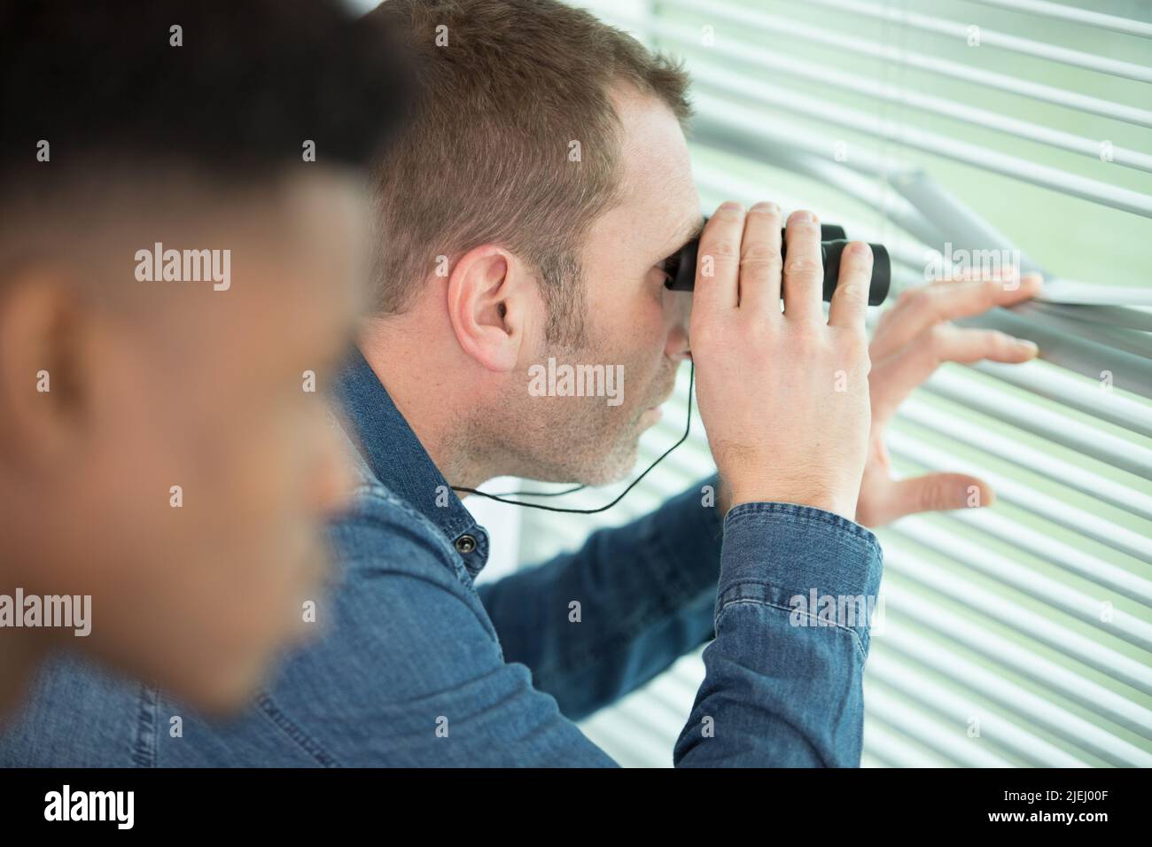 young man looks out the window with binoculars close-up Stock Photo - Alamy