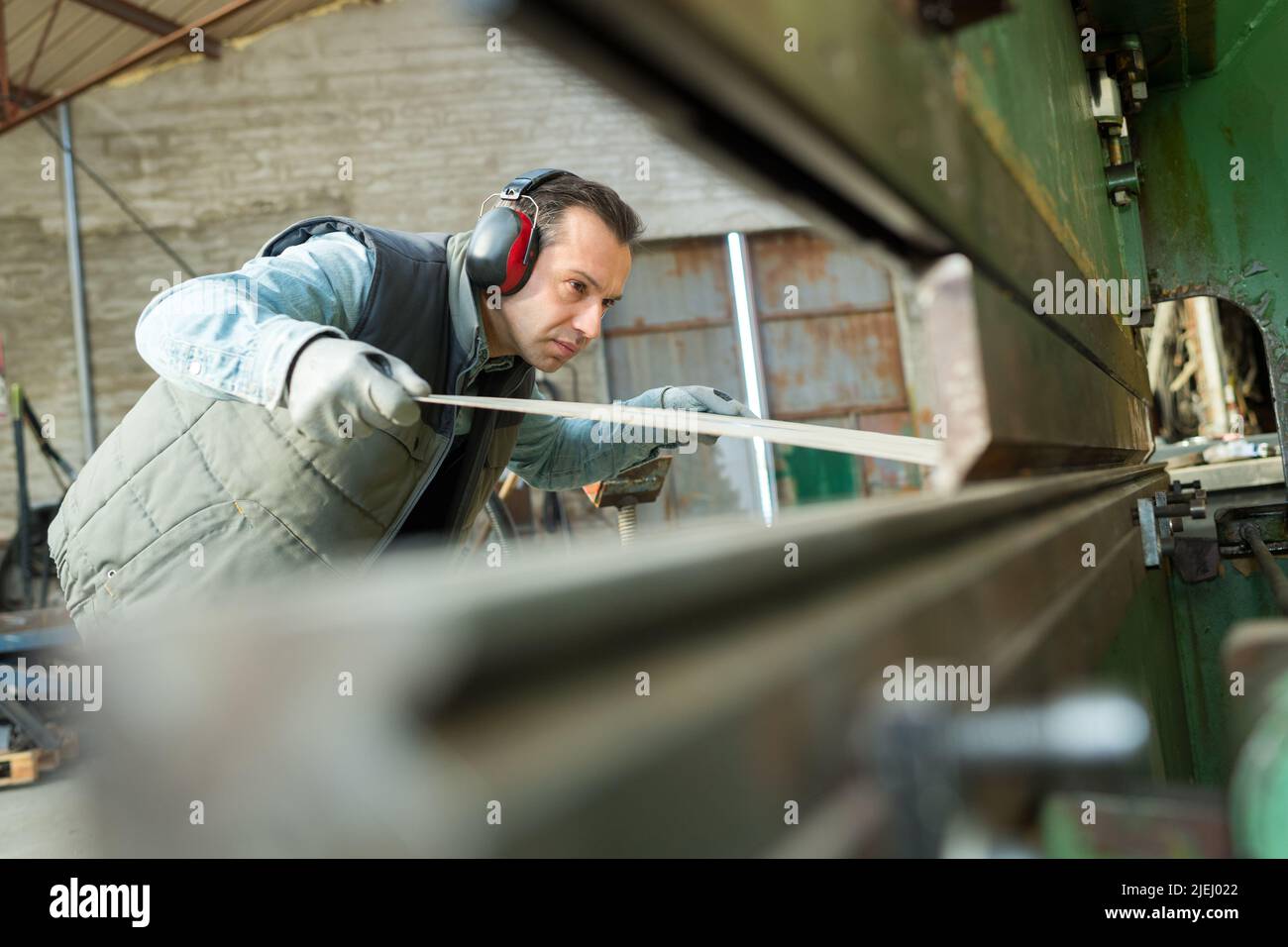worker passing sheet metal through industrial machine Stock Photo - Alamy