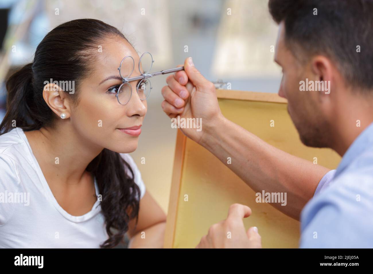 optician holding lenses over patients eyes to test her sight Stock ...