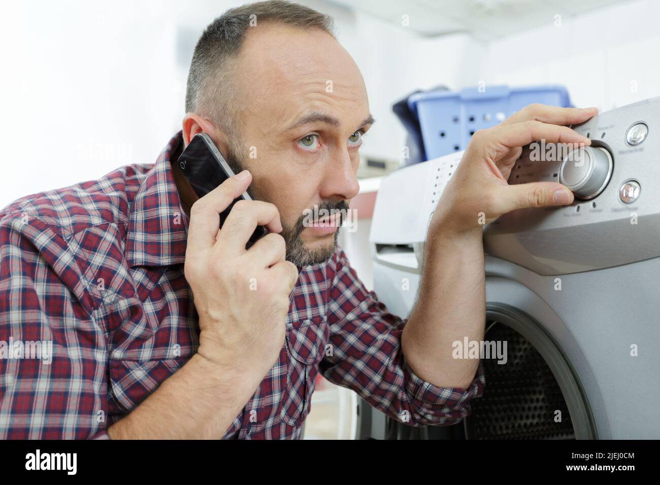man talking onphone while putting laundry in washing machine Stock ...