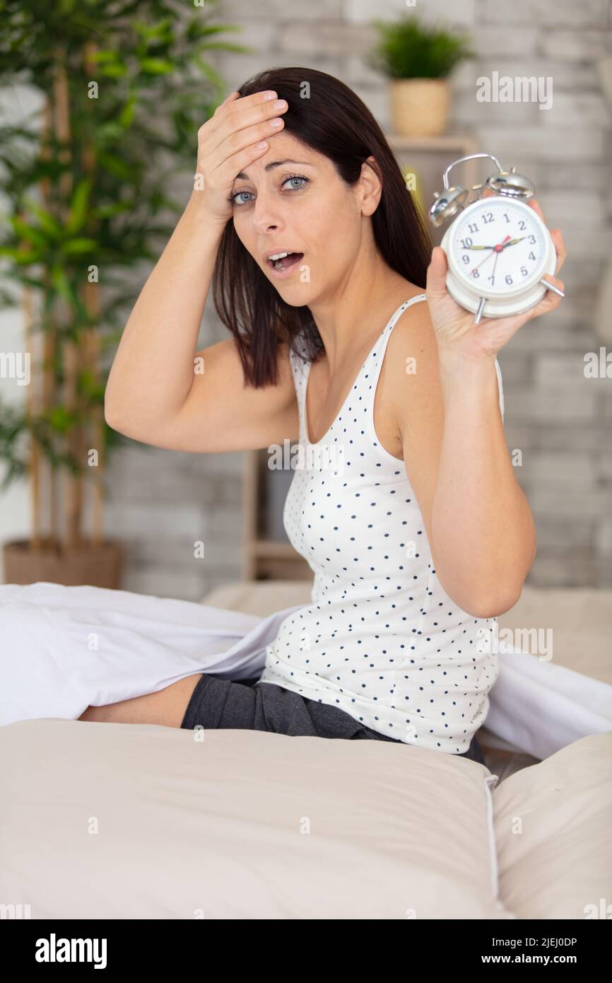 frustrated woman holding alarm clock Stock Photo - Alamy