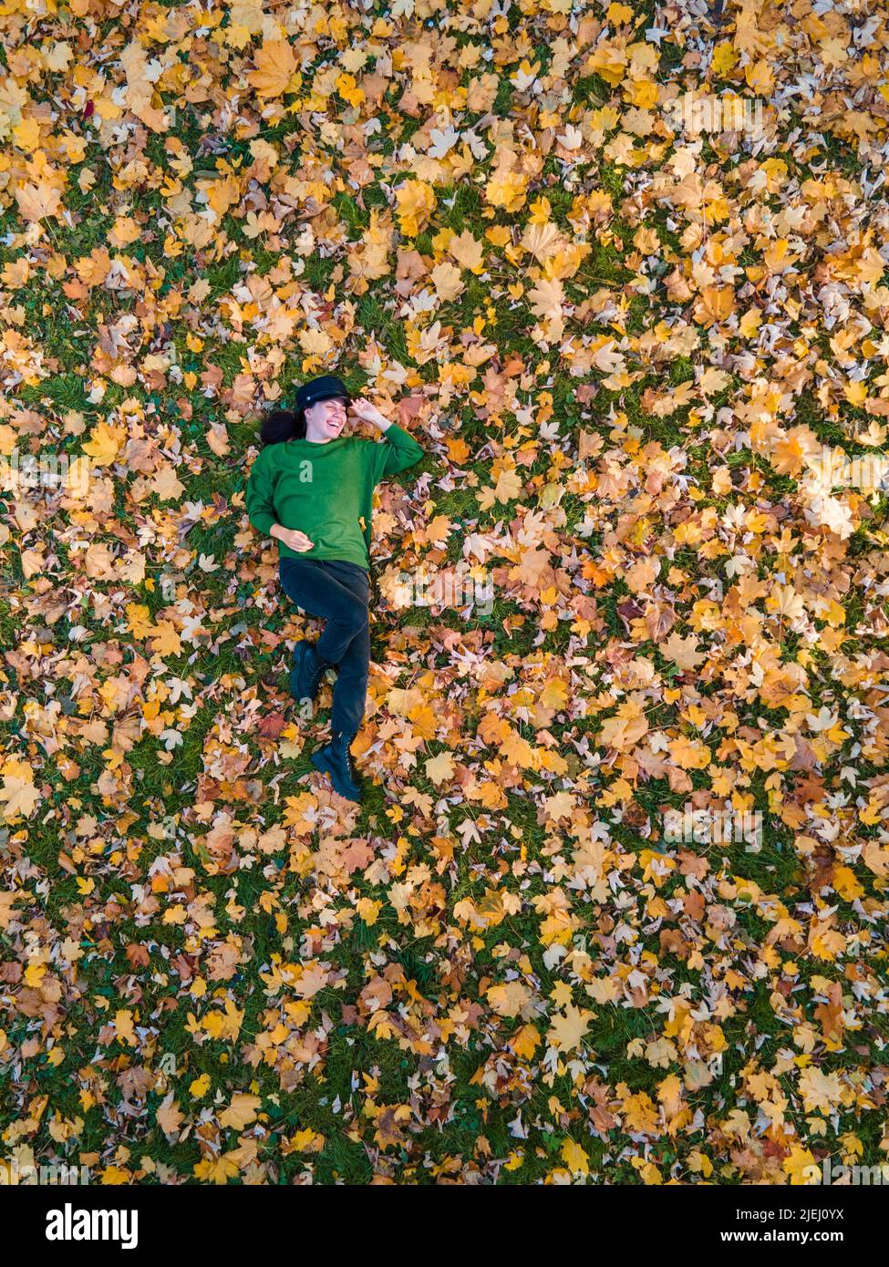 overhead view smiling woman laying on the ground covered with yellow ...