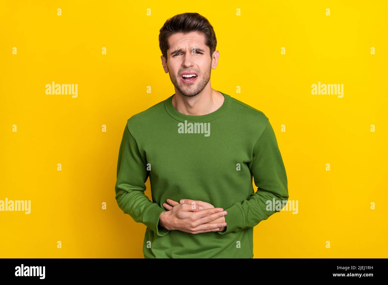 Photo of unhappy upset guy wear green sweater arms stomach having pain ...