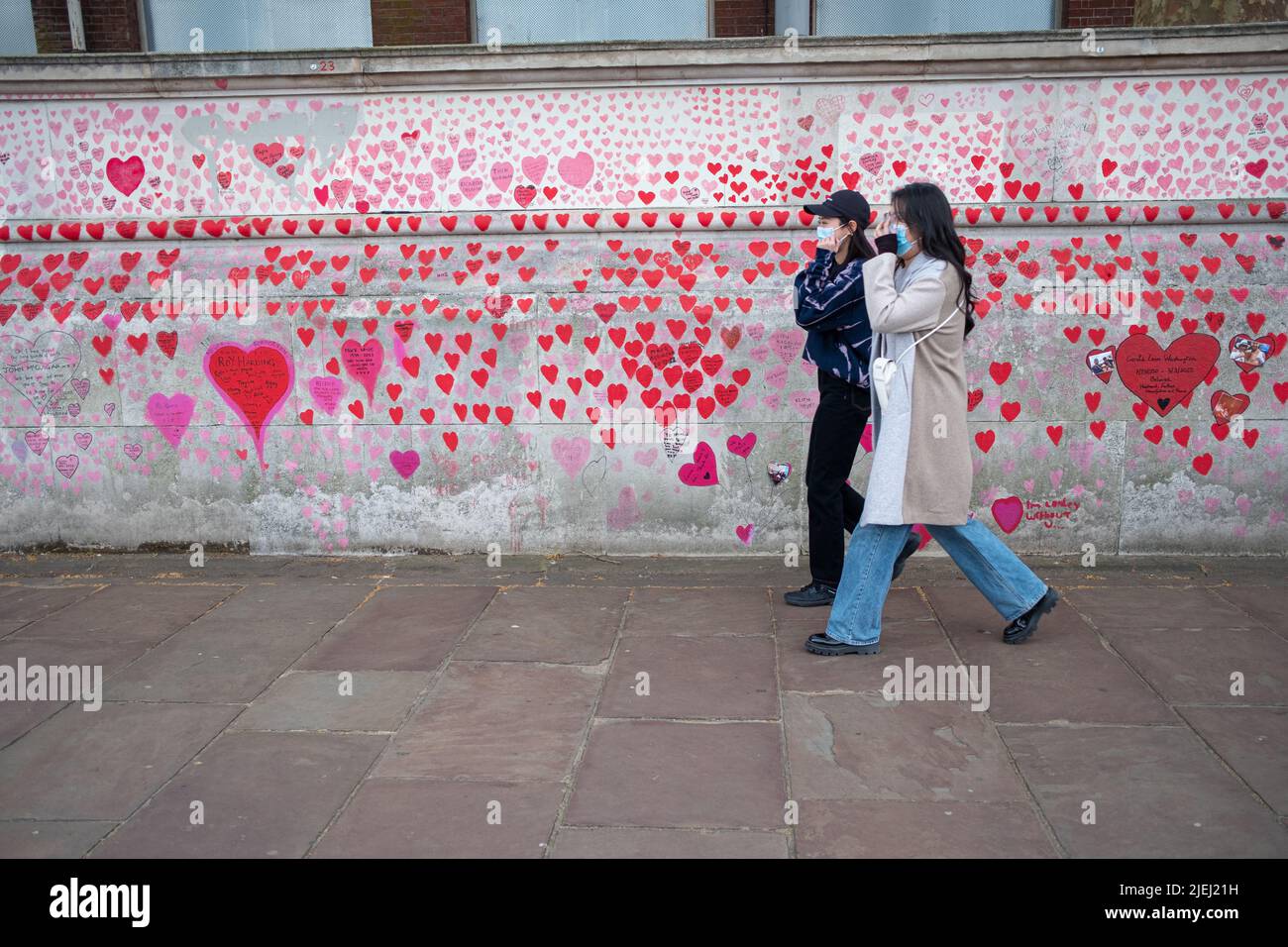 Two women wearing face masks walking in front of the National Covid ...