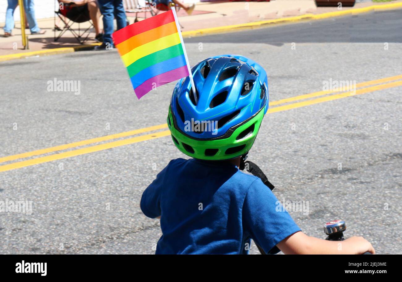 Gay pride rainbow flag sticking out of a small childs helmet as he ...