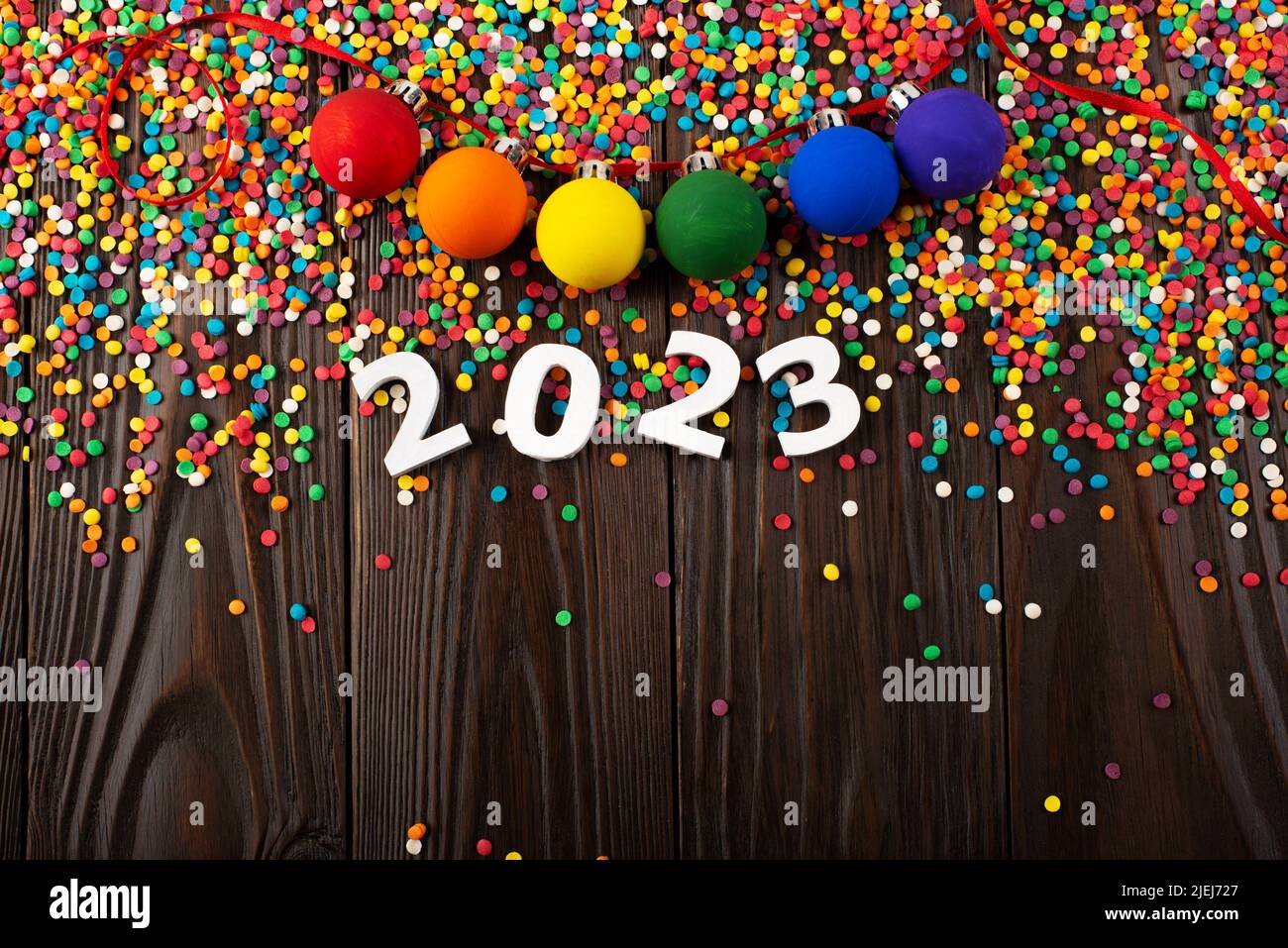 White numbers 2023 and color sugar sprinkles on wooden table with color ...