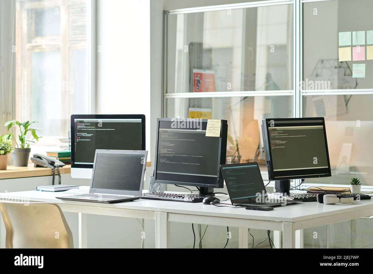 Horizontal image of workplace of IT specialist with codes on screens of computers and laptops on ...
