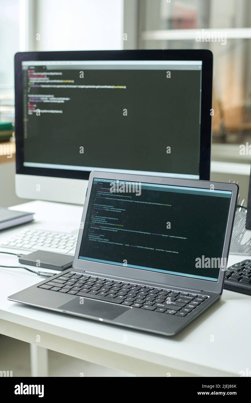 Close-up of workplace of programmer with laptop with codes on screen for installation new ...