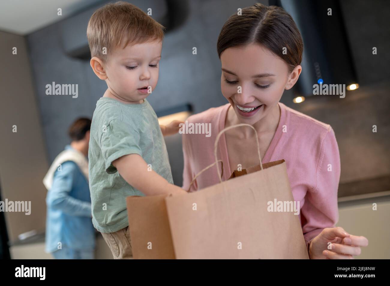 Young mom with a little kid opening bags with food in the kitchen Stock ...