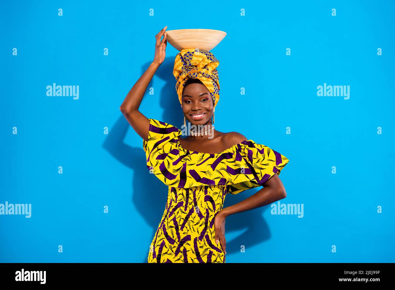 Photo of smiling beautiful positive afro woman hold clay plate on head ...