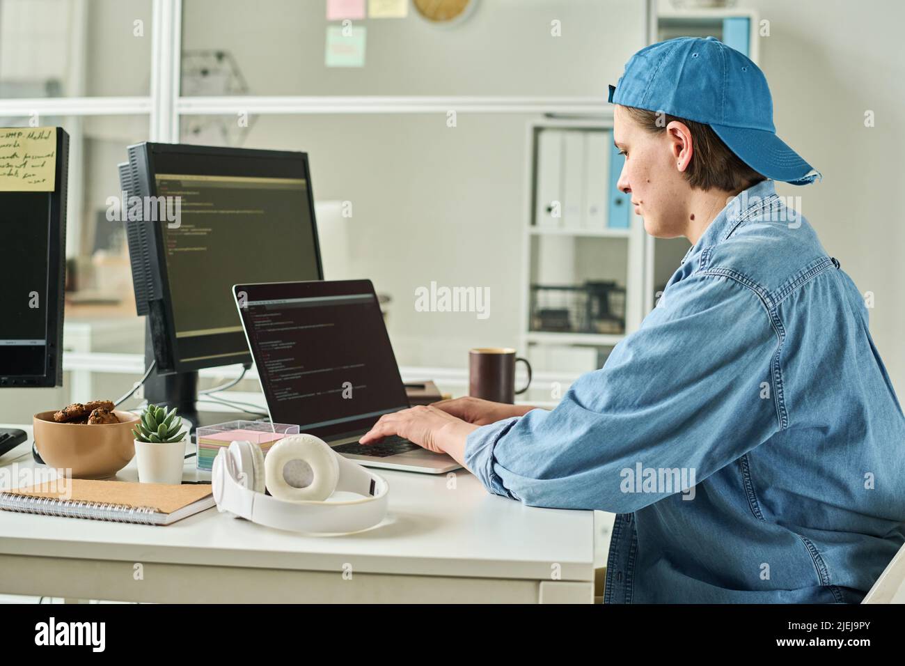 Female developer in casual clothing typing on laptop working over new ...
