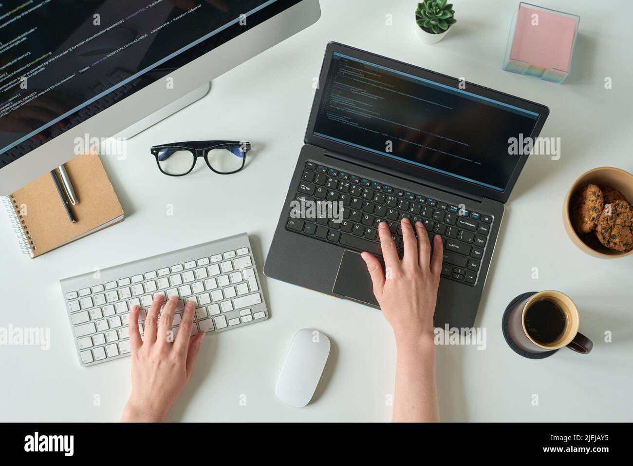 High angle view of young programmer writing code on laptop and using ...